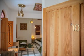 Uma porta de madeira com placa de número de latão, um quarto com piso estampado e luminárias pendentes.