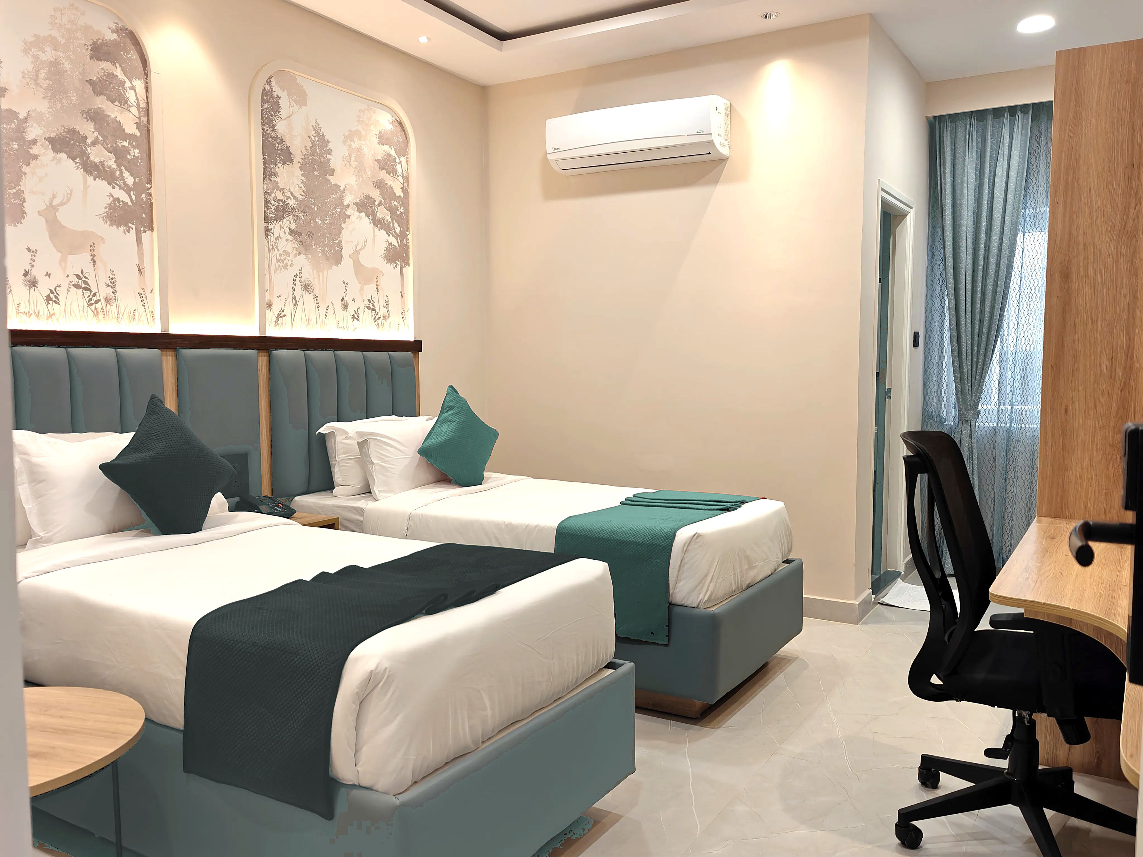 Quarto de hotel com duas camas, uma escrivaninha, uma cadeira e aparelho de ar condicionado.