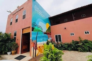 Um edifício com um mural de uma cena praiana, fachada vermelha e uma porta.