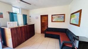 Uma área de recepção com uma mesa de madeira, um sofá e duas quadros na parede.