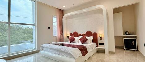 Quarto de hotel moderno com uma cama grande, uma kitchenette pequena e vista para o exterior.