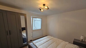 Quarto com cama, guarda-roupa, janela e luminária no teto.