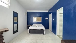 Quarto com cama, mesa de cabeceira, espelho e porta.