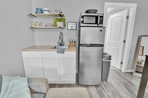 Uma cozinha compacta com micro-ondas e geladeira embutidos, bancada de madeira e pia.