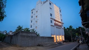 Um hotel de vários andares com uma placa grande, entrada com portão e vista para a rua.