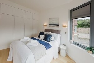 Quarto moderno com uma cama grande, vista para o exterior e espaço de armazenamento embutido.