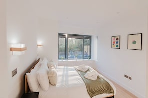 Quarto com cama, janela e luminárias fixadas na parede.