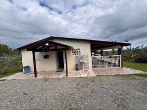 Um pequeno edifício com entrada coberta, uma janela e uma porta.