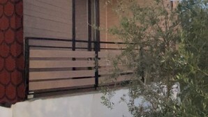 Um edifício moderno com teto plano, porta e um pequeno alpendre com guarda-corpo.