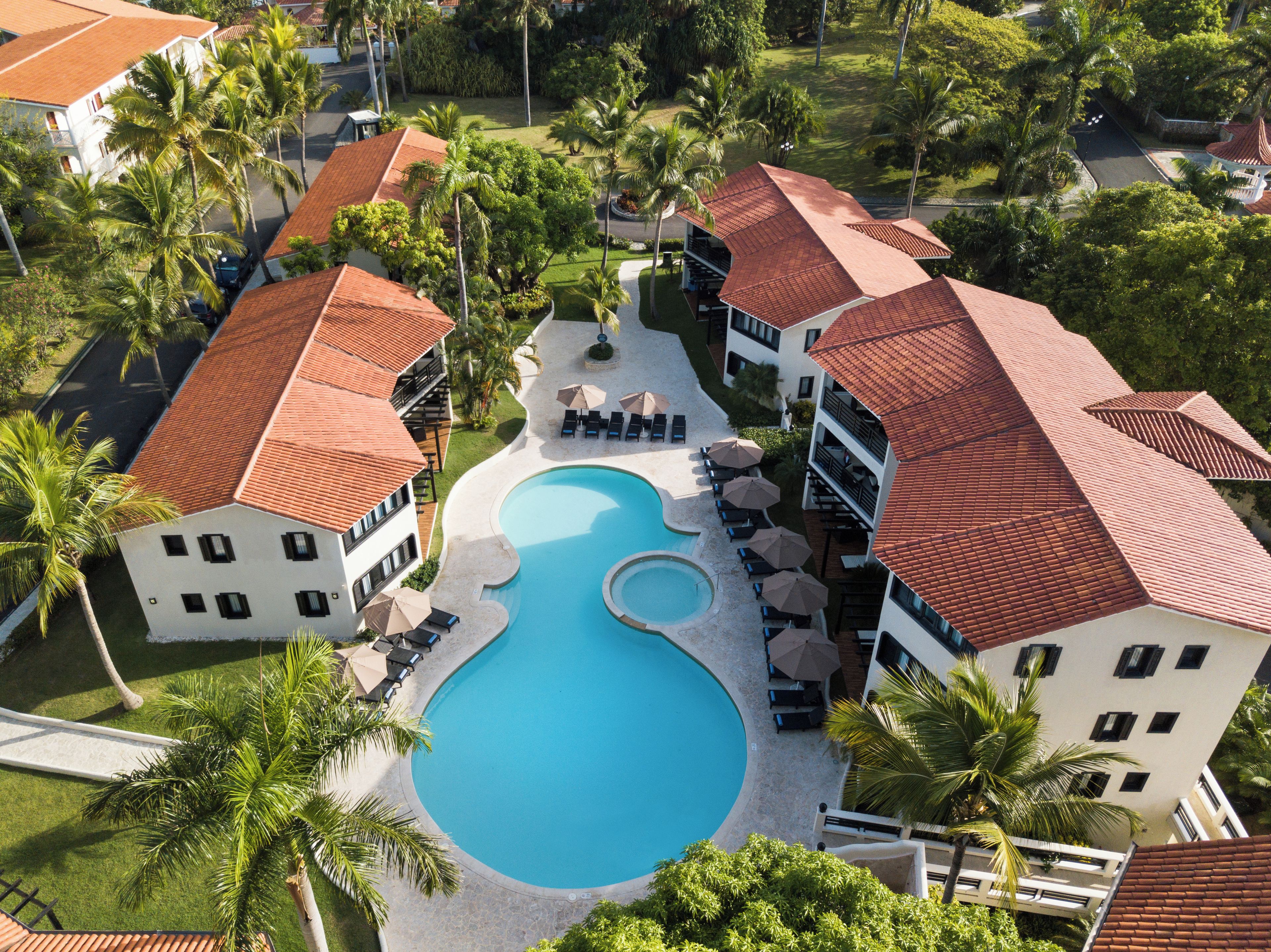 Um resort com uma piscina central, diversas áreas de estar e um jardim bem cuidado.