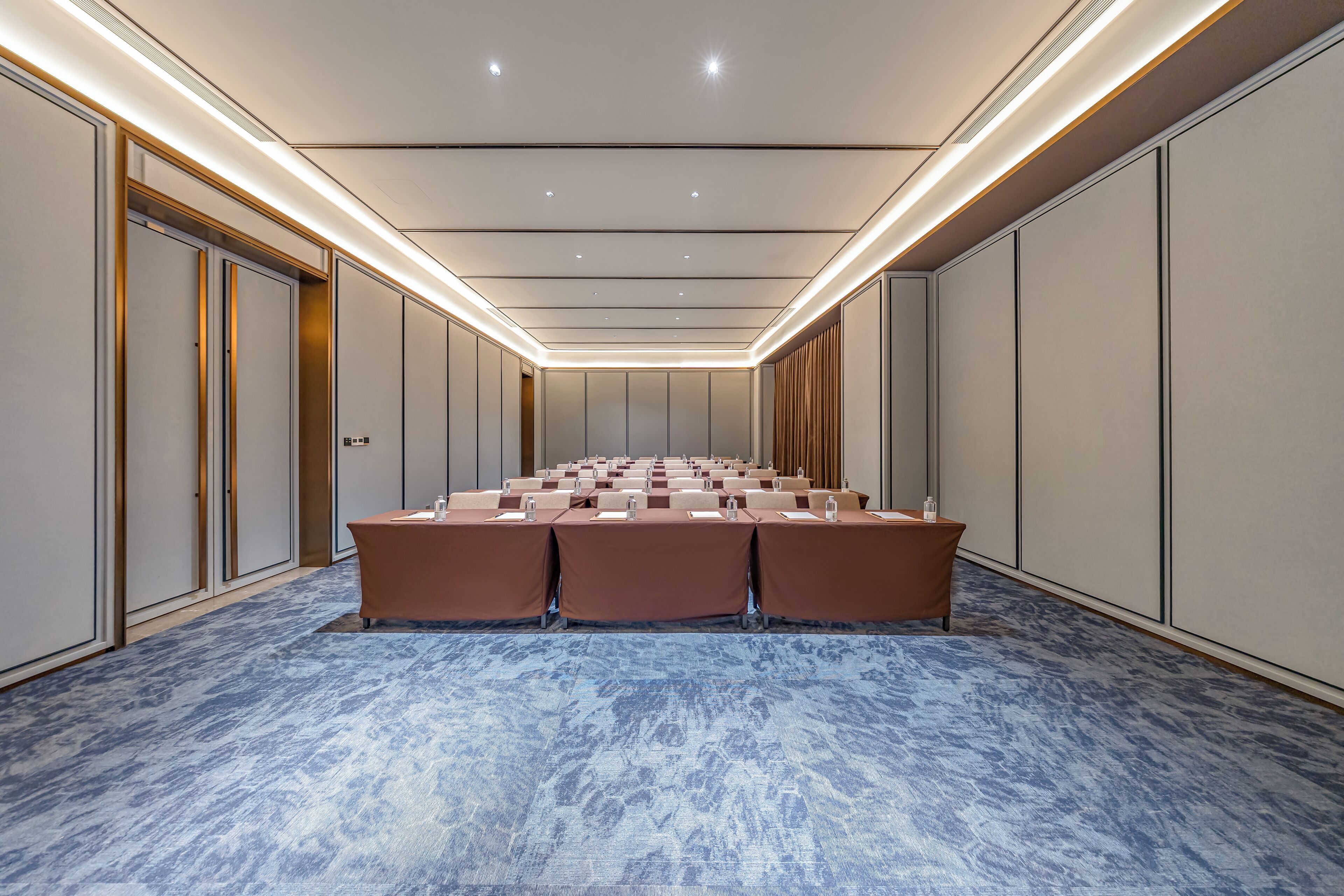 Uma sala de conferências com uma mesa comprida, cadeiras e piso coberto de carpete.