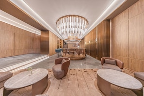 Um lobby com bar central, áreas de estar e luminária decorativa no teto.