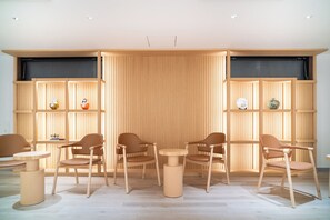 Um interior moderno com painéis de madeira, uma área de estar central com cadeiras e uma mesa redonda, e prateleiras com objetos decorativos.