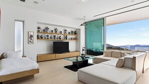 Uma sala de estar moderna com uma cama, sofá, televisão e estantes com figuras.