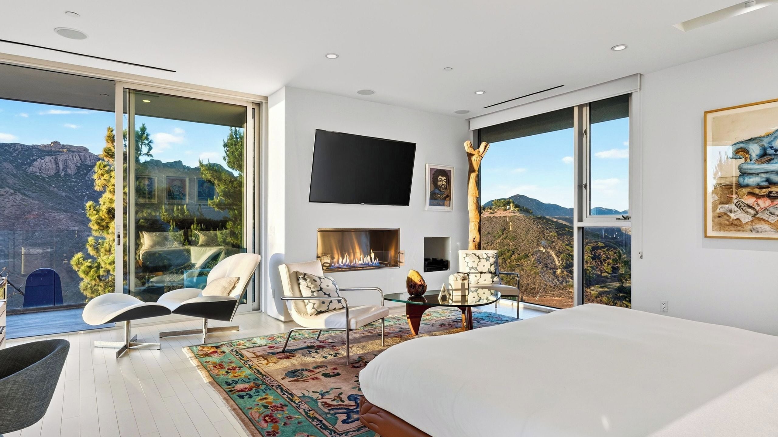 Quarto moderno com uma cama grande, lareira e vista panorâmica das montanhas.