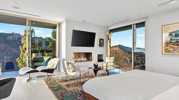 Quarto moderno com uma cama grande, lareira e vista panorâmica das montanhas.