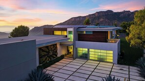 Uma casa moderna com telhado plano, janelas grandes e vista para as montanhas.