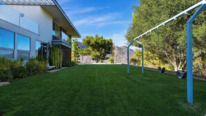 Uma casa moderna com um gramado bem cuidado, balanço e vista para as montanhas.