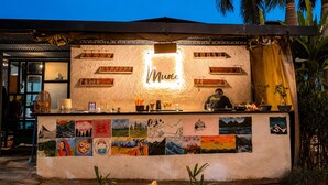 Um bar com uma placa de neon, prateleiras com garrafas e uma parede decorada com pinturas coloridas.