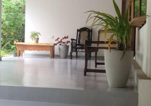 Um quarto com um banco de madeira, uma planta em vaso, uma cadeira e uma mesa.