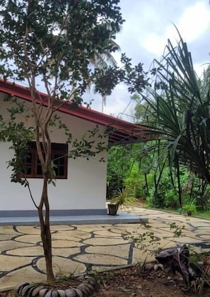 Um edifício com telhado vermelho, uma janela e um espaço pavimentado com desenhos circulares.