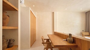 Quarto minimalista com mesa de madeira, uma cadeira e uma estante com cerâmica.