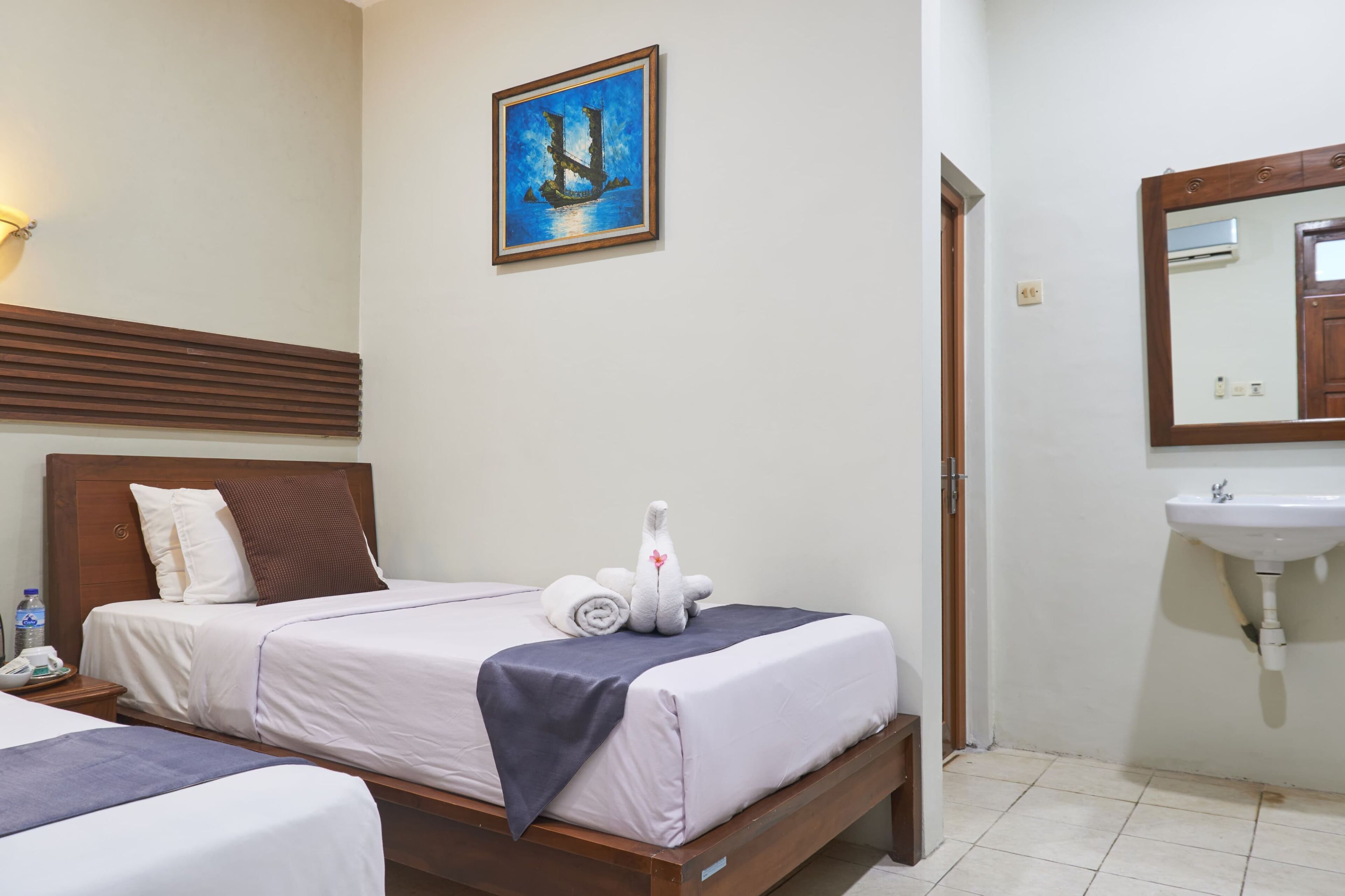 Quarto de hotel com cama, um quadro, banheiro com pia e espelho.