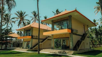 Um edifício moderno de dois andares com telhado plano, grandes janelas de vidro e uma escadaria central.