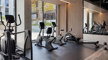 Uma academia com diversos equipamentos de exercício, grandes janelas e um design de interiores moderno.