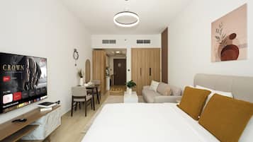 Quarto de hotel moderno com uma cama, televisão, área de refeições e cozinha.