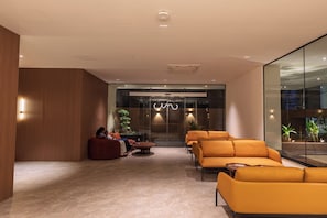 Um interior moderno com área de estar, parede de vidro e luminária no teto.