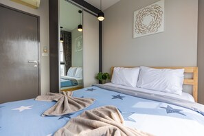 Quarto com cama, mesa de cabeceira, espelho e obra de arte na parede.