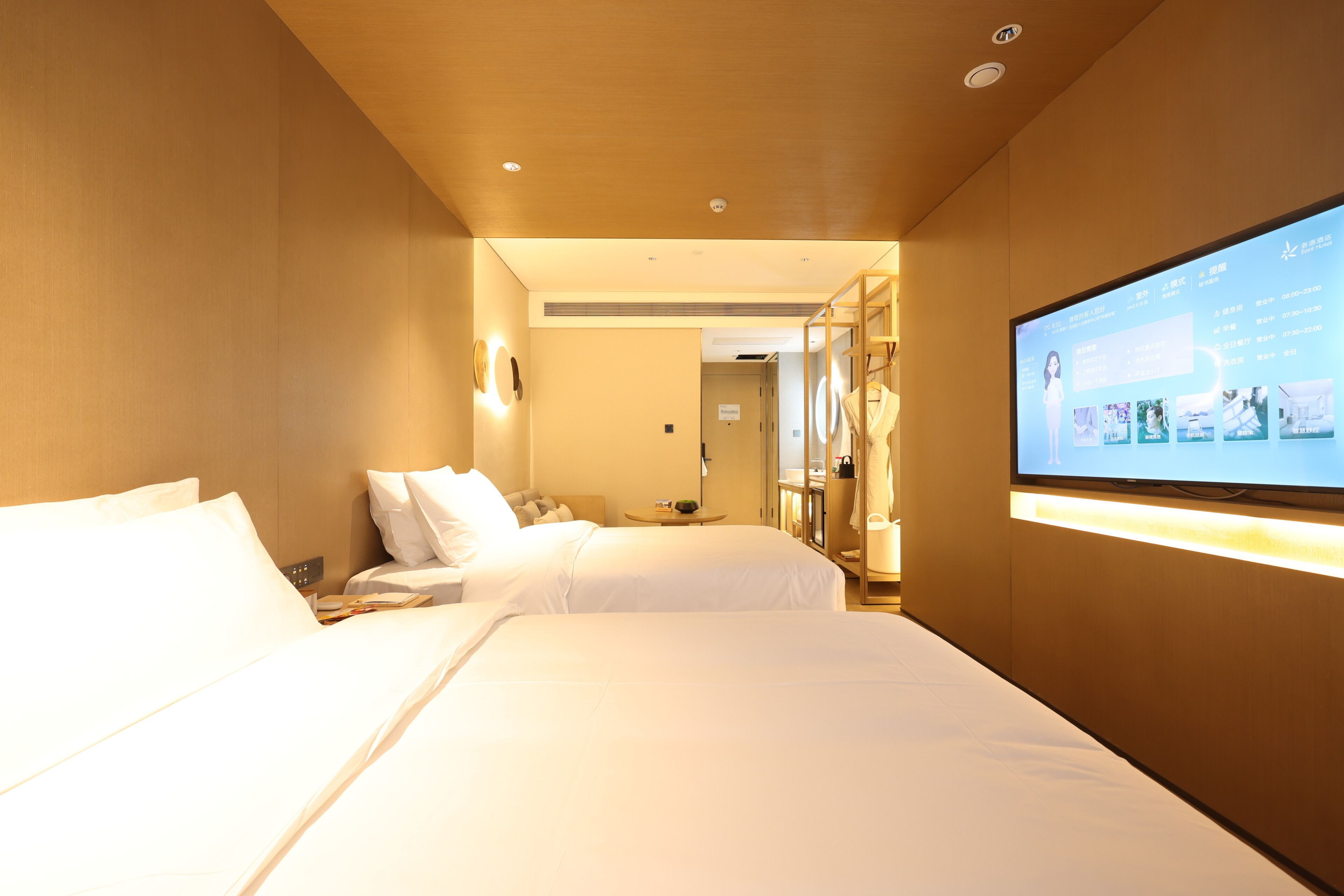 Quarto de hotel com duas camas, uma televisão exibindo um menu e teto de madeira.