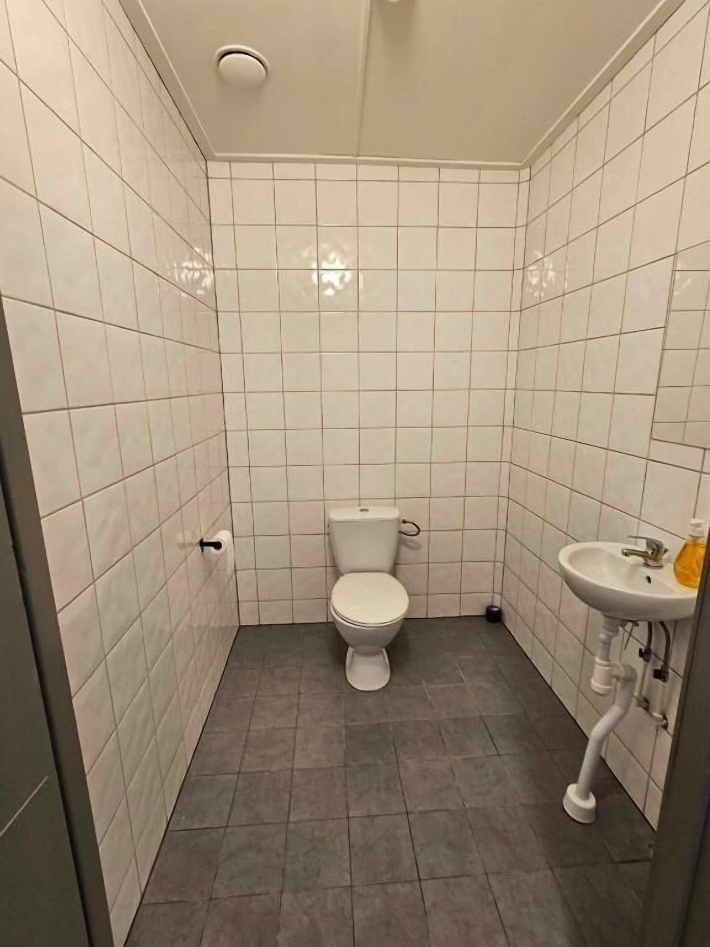 Uma casa de banho pequena com azulejos, com sanita e lavatório.