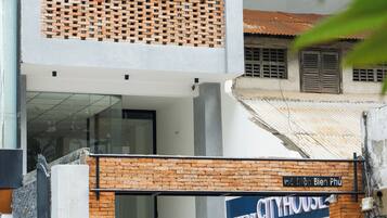 Um edifício com fachada de tijolos, uma placa com a inscrição 'CITYHOUSE' e um portão vermelho.