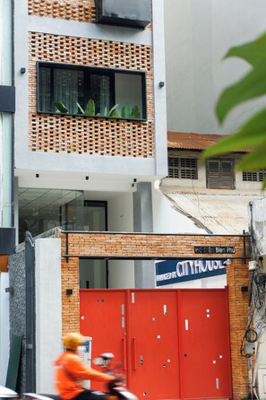 Um edifício com fachada de tijolos, uma placa com a inscrição 'CITYHOUSE' e um portão vermelho.