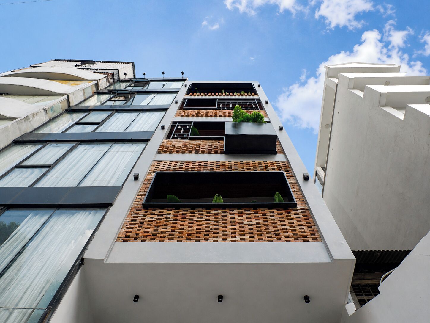 Um edifício moderno com várias varandas, janelas amplas e céu claro.