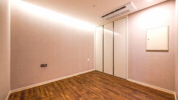 Quarto com piso de madeira, porta deslizante e ar-condicionado fixado na parede.