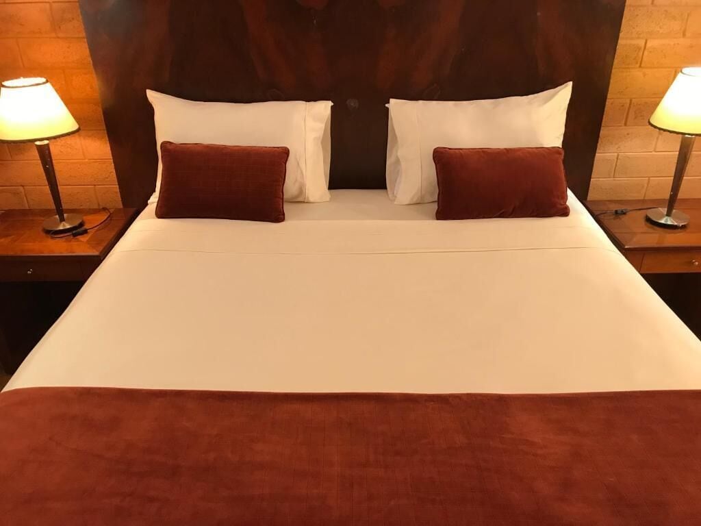 Quarto de hotel com uma cama, duas mesas de cabeceira e luminárias.