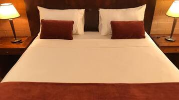 Quarto de hotel com uma cama, duas mesas de cabeceira e luminárias.