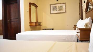 Quarto de hotel com cama, cómoda de madeira, espelho e quadro pendurado na parede.
