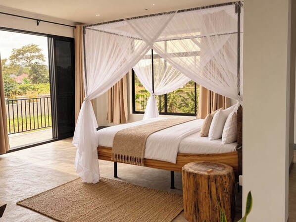 Quarto com cama de dossel, grandes janelas, vista para o verde e piso de madeira.