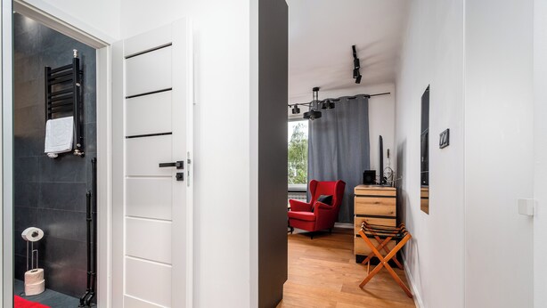 Um interior moderno com uma porta branca, uma cadeira vermelha e uma escrivaninha de madeira.