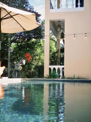 Uma piscina com vista clara da água, rodeada por um edifício com varanda e luzes de Natal.