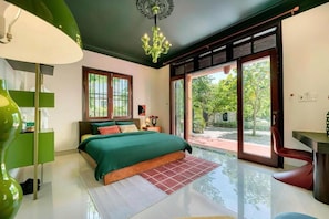 Quarto com cama, escrivaninha, cadeira e vista para o exterior.