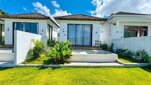 Uma casa moderna com piscina, alpendre coberto e gramado bem cuidado.