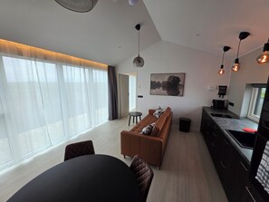 Uma sala de estar moderna com sofá, mesa de jantar e área de cozinha.