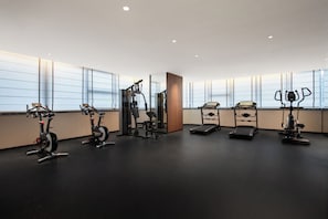 Academia moderna com diversos equipamentos de exercício, grandes janelas e design limpo e minimalista.