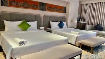 Quarto de hotel com duas camas, um sofá e uma escrivaninha.
