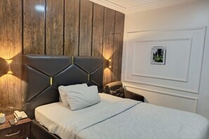 Quarto de hotel com uma cama, mesa de cabeceira, telefone e um quadro na parede.